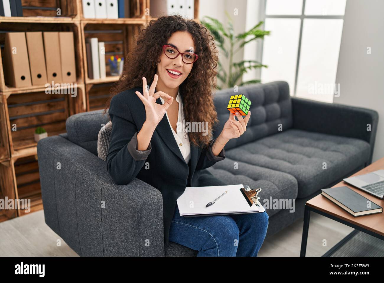 Young hispanic woman playing colorful puzzle cube intelligence game ...