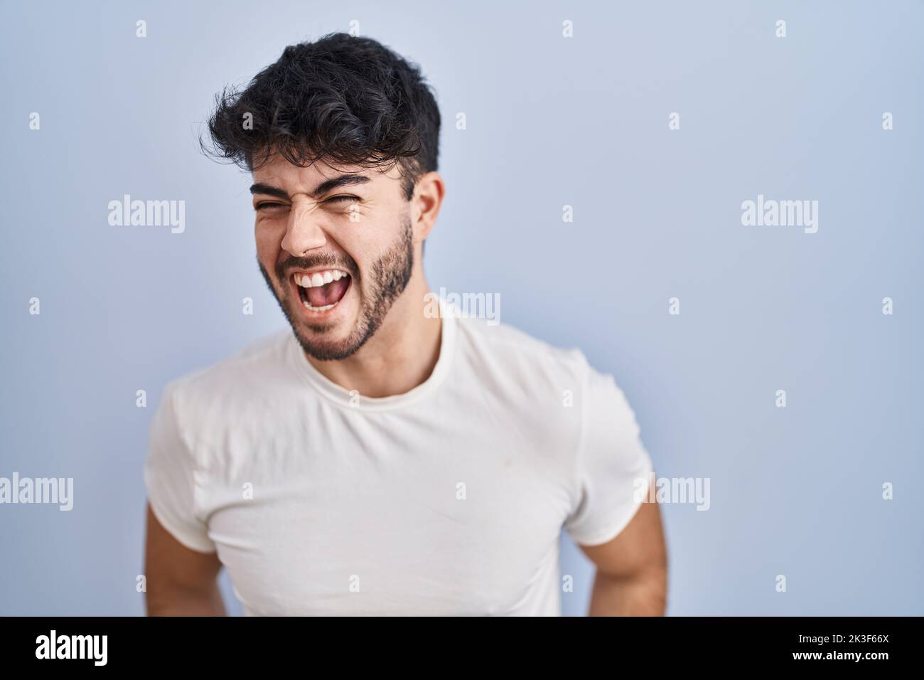 Hispanic man with beard standing over white background angry and mad ...