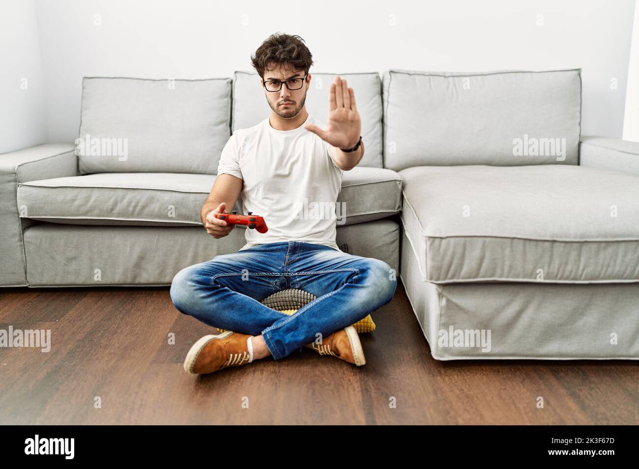 Hispanic man playing video game holding controller by the sofa with ...