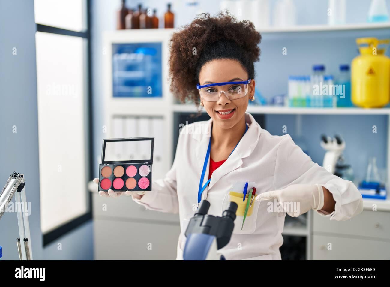 Young african american woman working at scientist laboratory doing make ...