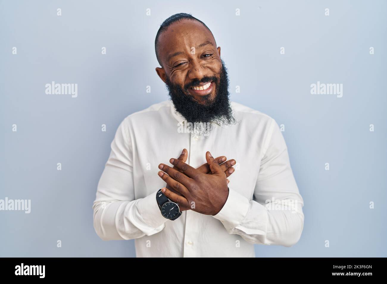 African american man standing over blue background smiling with hands ...