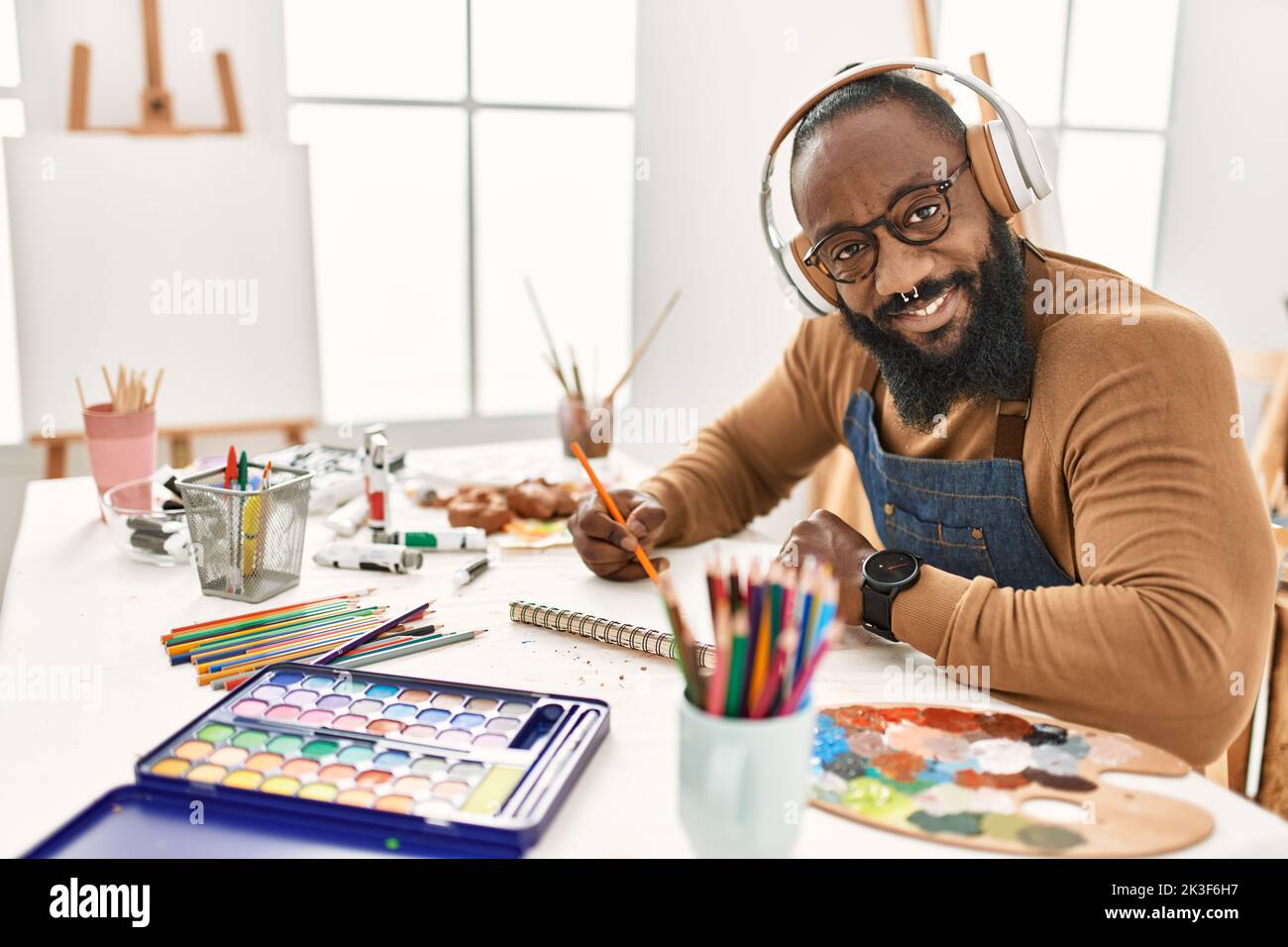 Young african american artist man using headphones drawing at art ...