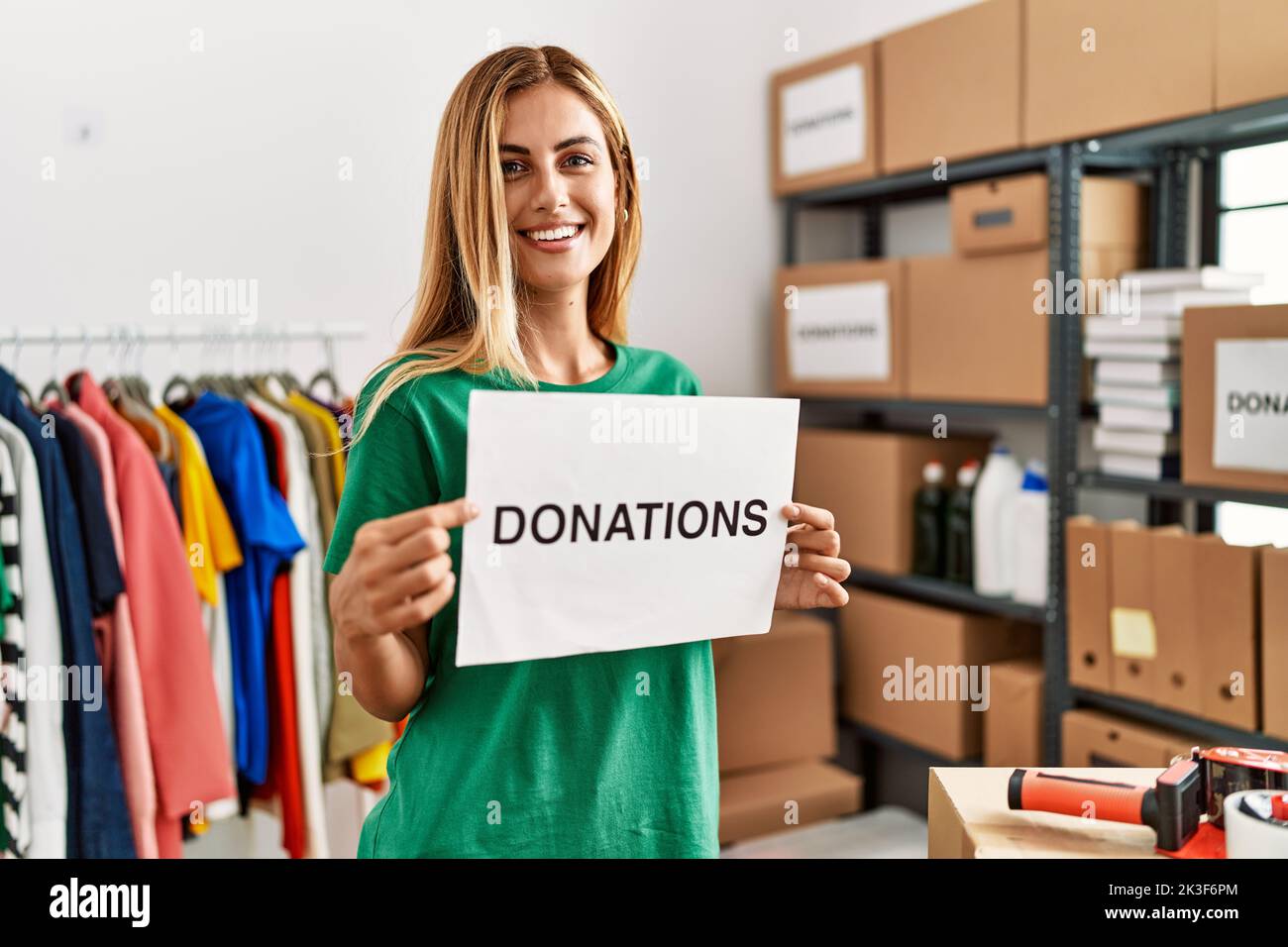 Young caucasian volunteer girl smiling happy holding donations banner ...