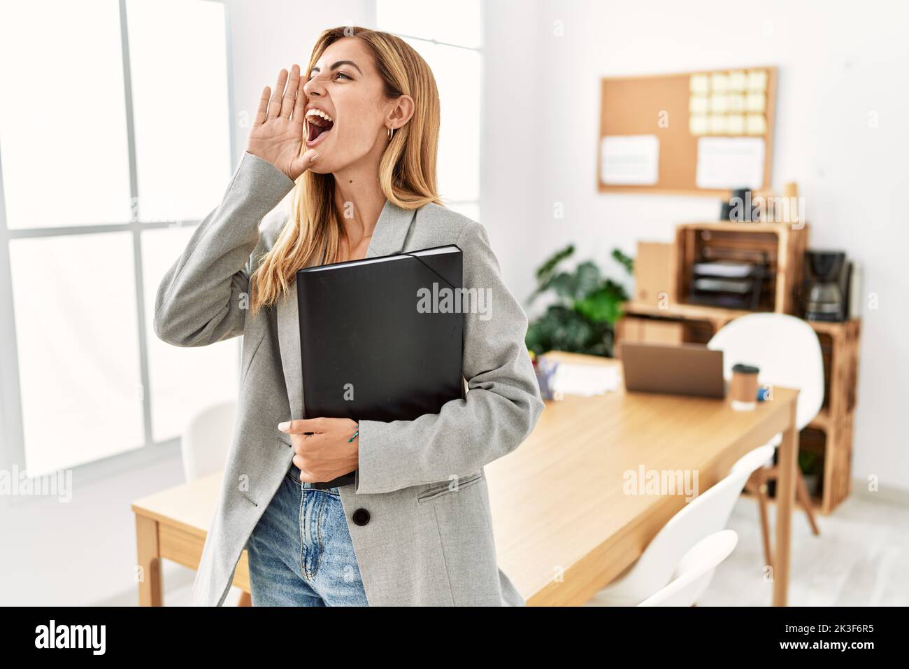 Blonde business woman at the office shouting and screaming loud to side ...