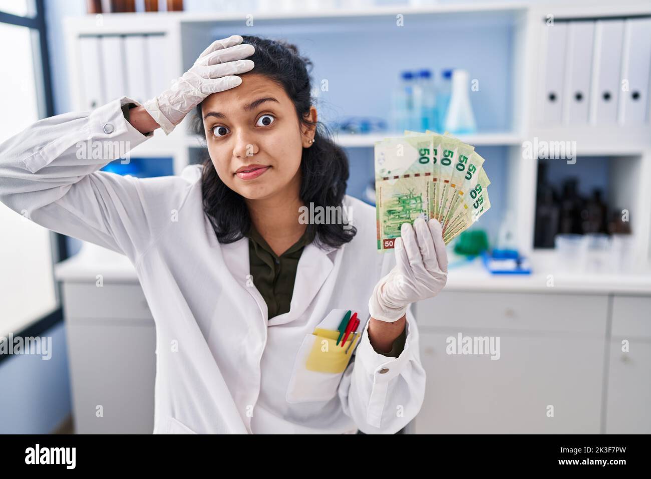 Hispanic woman with dark hair working at scientist laboratory holding ...