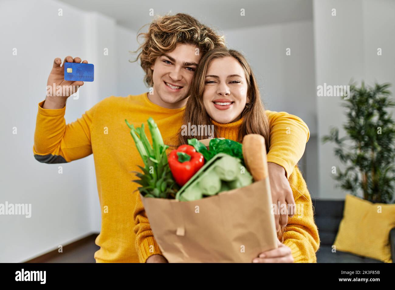Young caucasian couple holding groceries paper bag and credit card ...