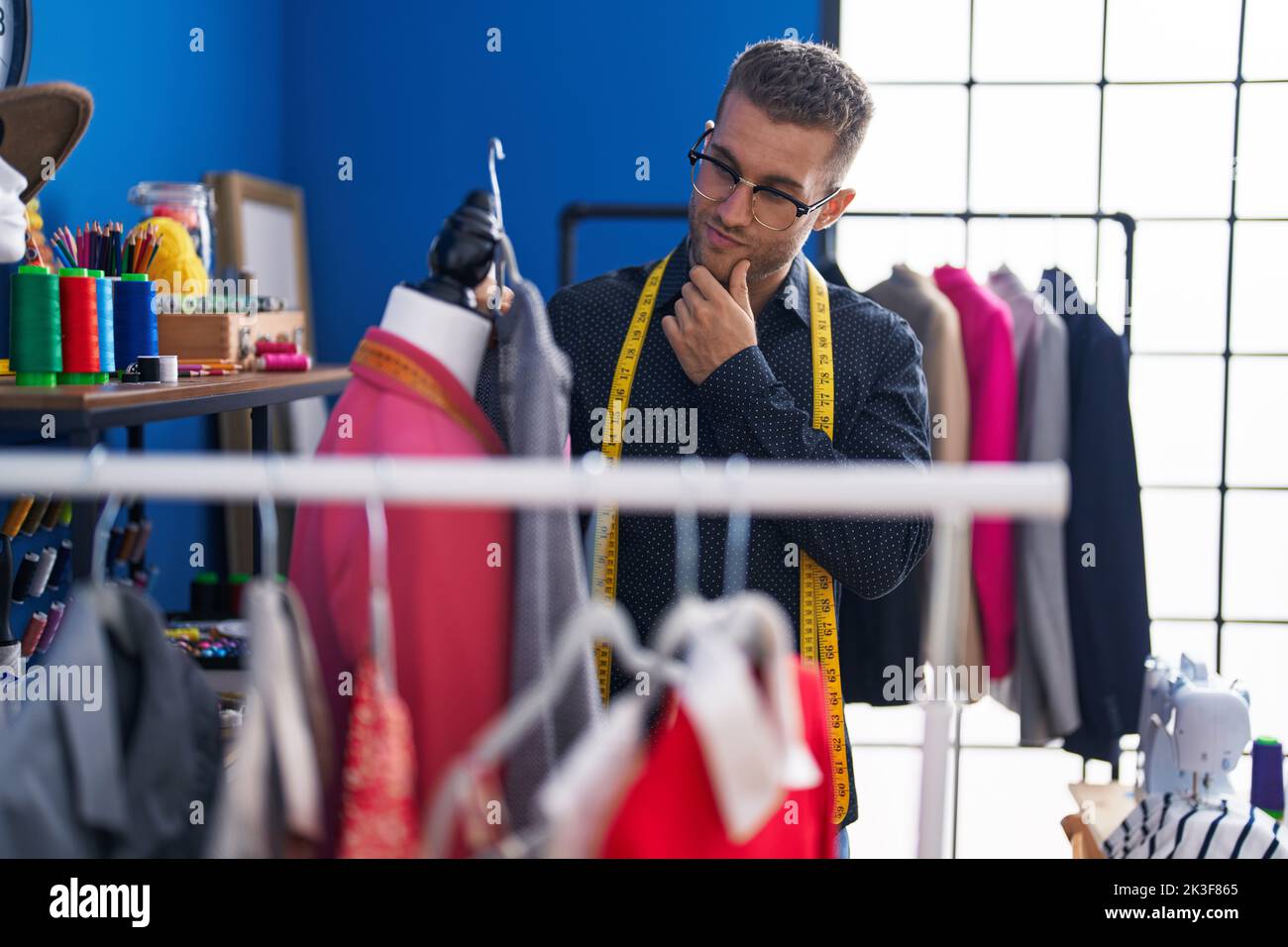 Young caucasian man tailor holding shirt with doubt expression at ...