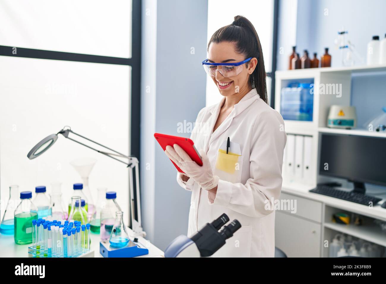 Young beautiful hispanic woman scientist smiling confident using touchpad at laboratory Stock ...