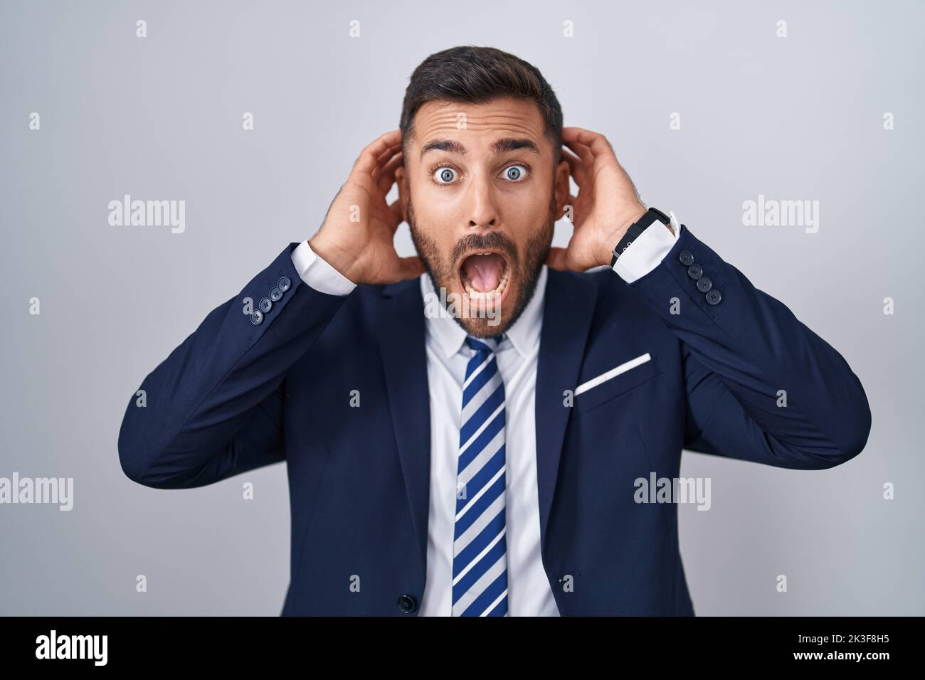 Handsome hispanic man wearing suit and tie crazy and scared with hands ...