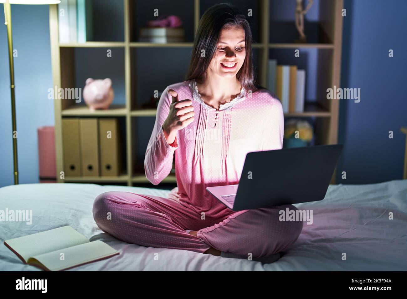 Young hispanic woman using computer laptop on the bed doing happy ...