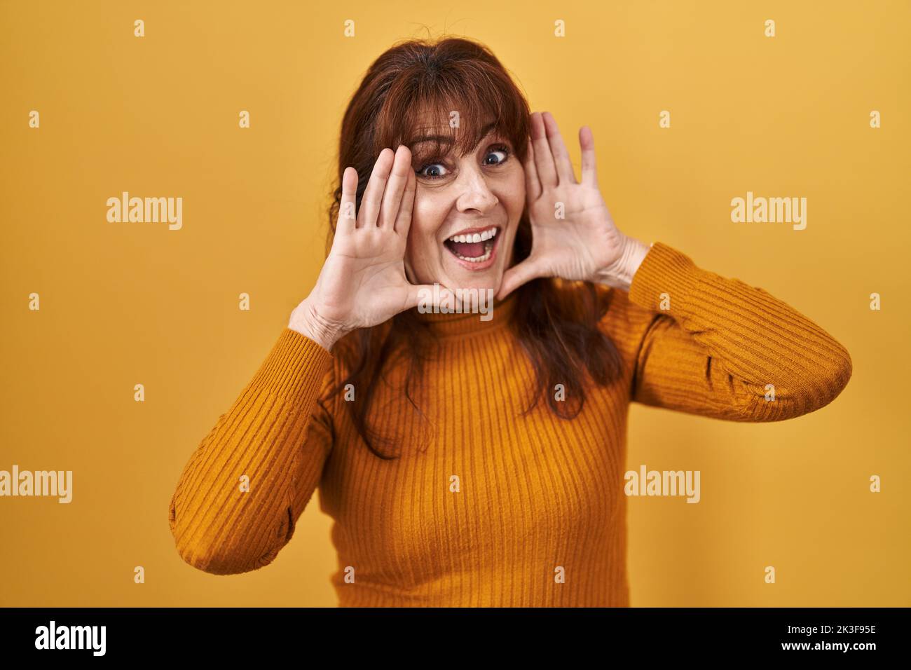 Middle age hispanic woman standing over yellow background smiling ...