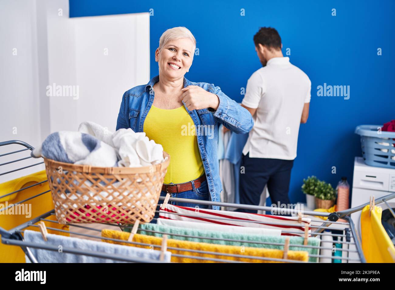 Hispanic mother and son hanging clothes at clothesline pointing finger ...