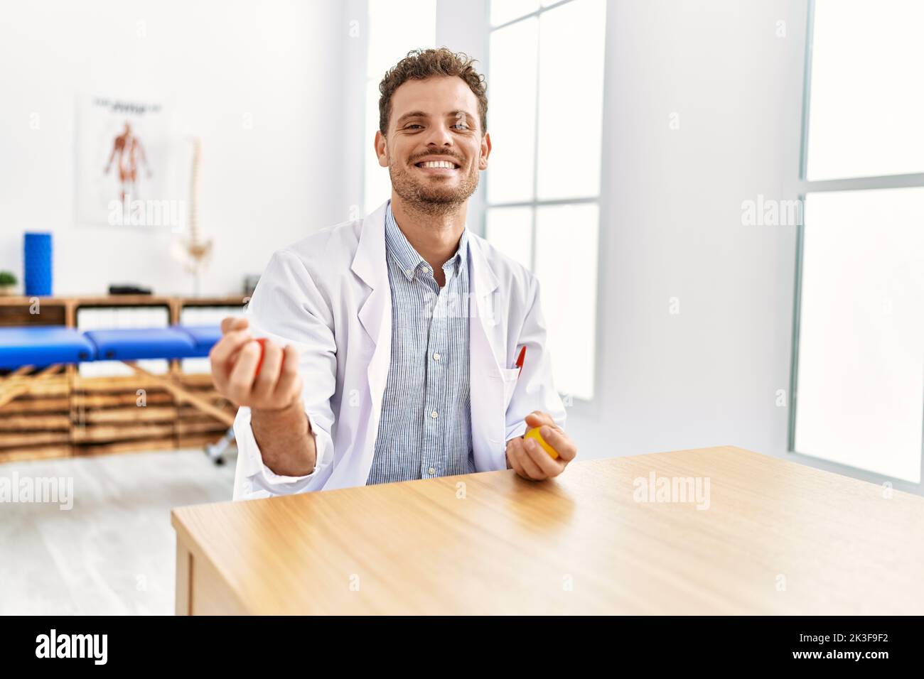 Young hispanic man wearing physiotherapist uniform press anti stress ...