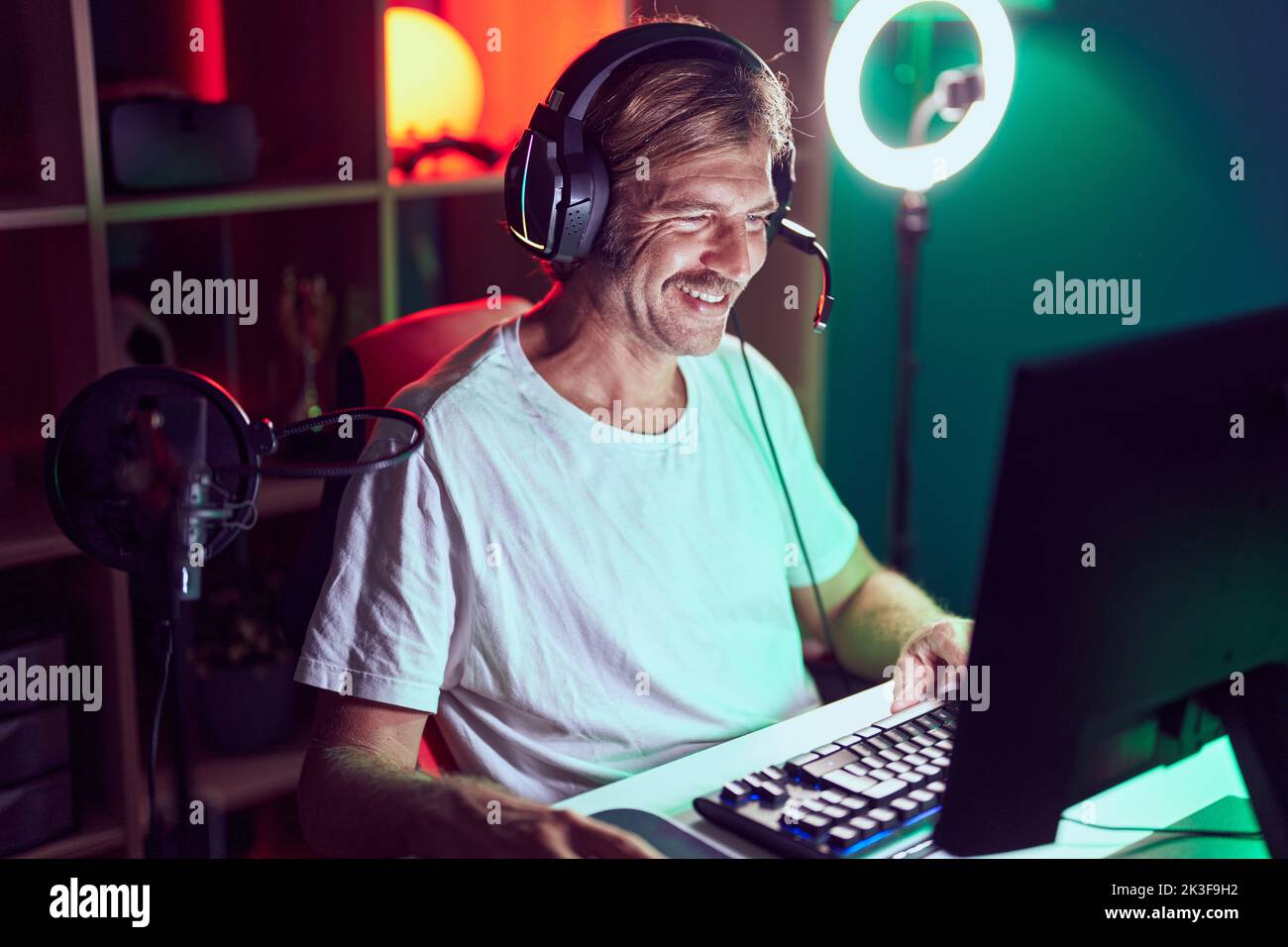 Young blond man streamer playing video game using computer at gaming ... Young blond man streamer playing video game using computer at gaming ...