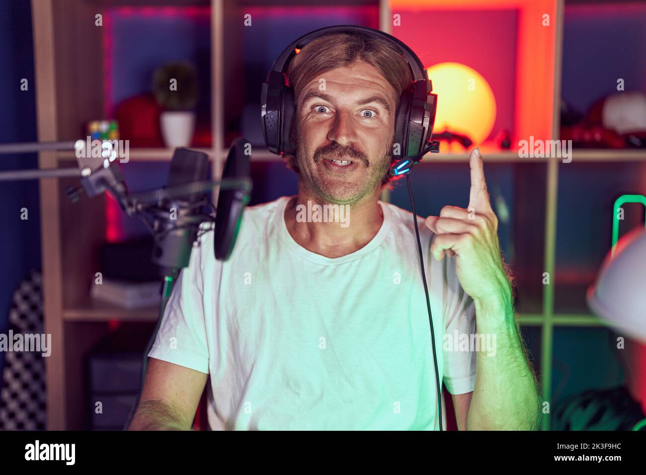 Caucasian man with mustache playing video games wearing headphones ...