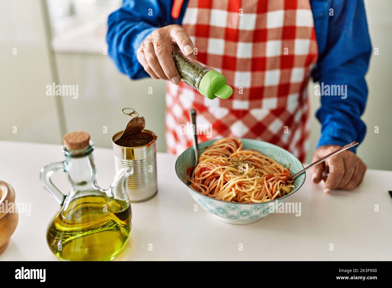 Senior man pouring oregano on spaghetti at kitchen Stock Photo - Alamy
