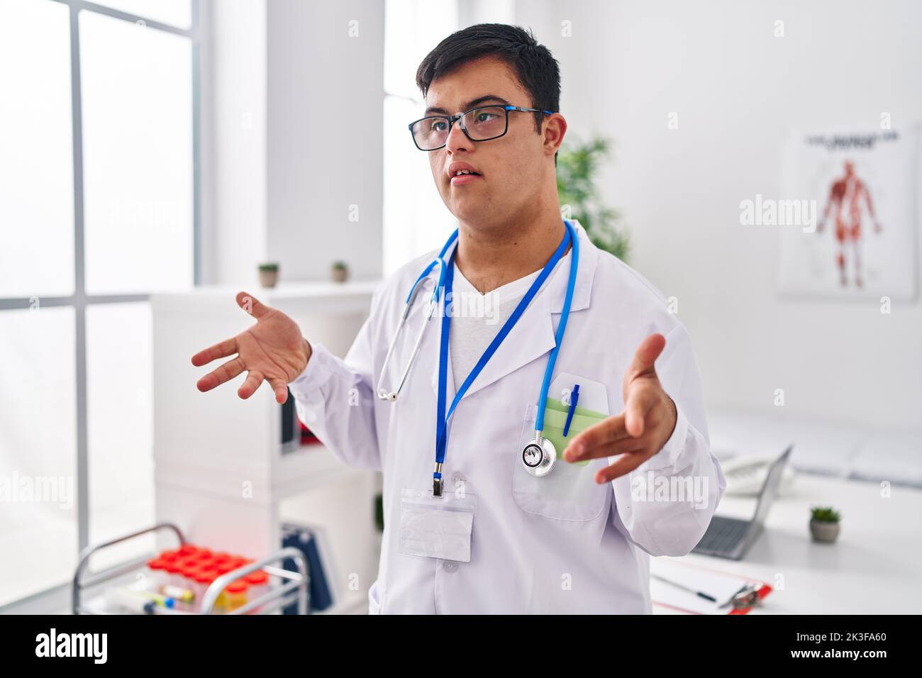 Down syndrome man wearing doctor uniform speaking at clinic Stock Photo ...