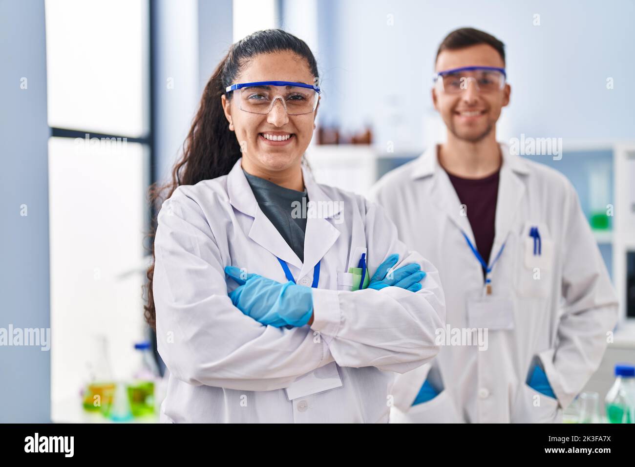 Man and woman wearing scientist uniform standing with arms crossed ...