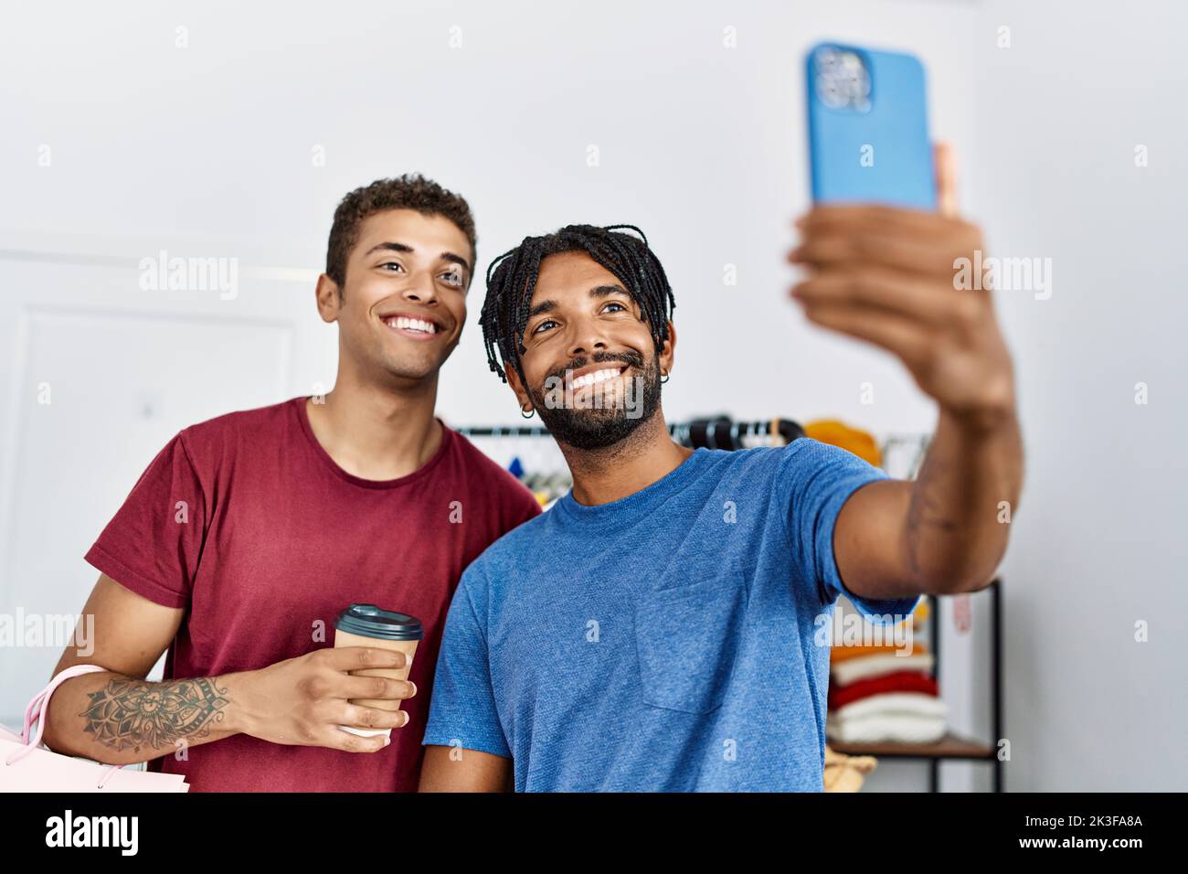 Two men friends holding shopping bags make selfie by the smartphone at ...