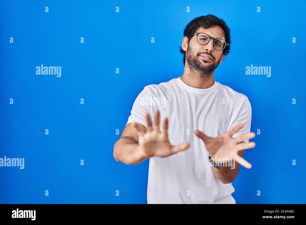 Handsome latin man standing over blue background disgusted expression ...