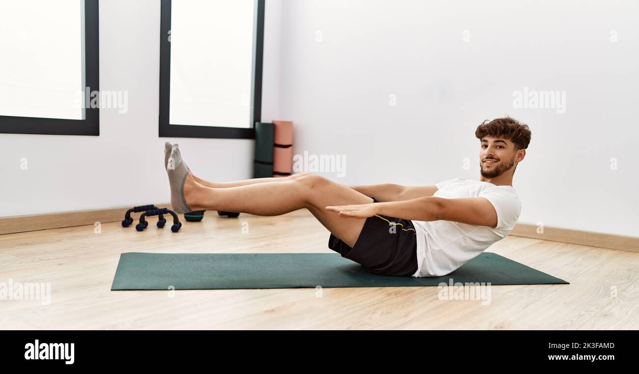 Young arab man smiling confident training abs exercise at sport center ...