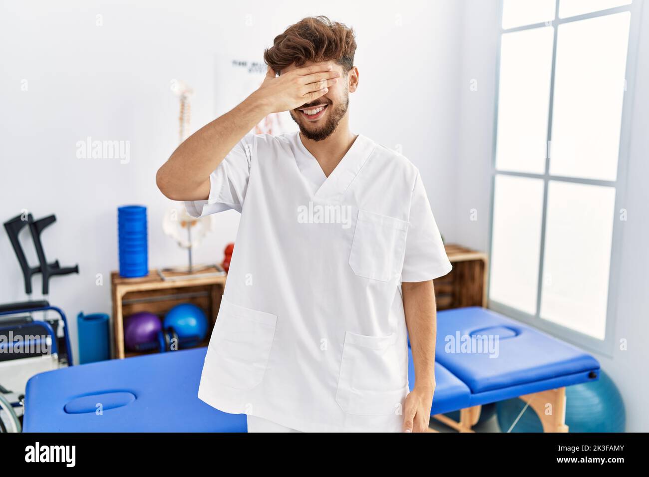 Young arab man working at pain recovery clinic smiling and laughing ...