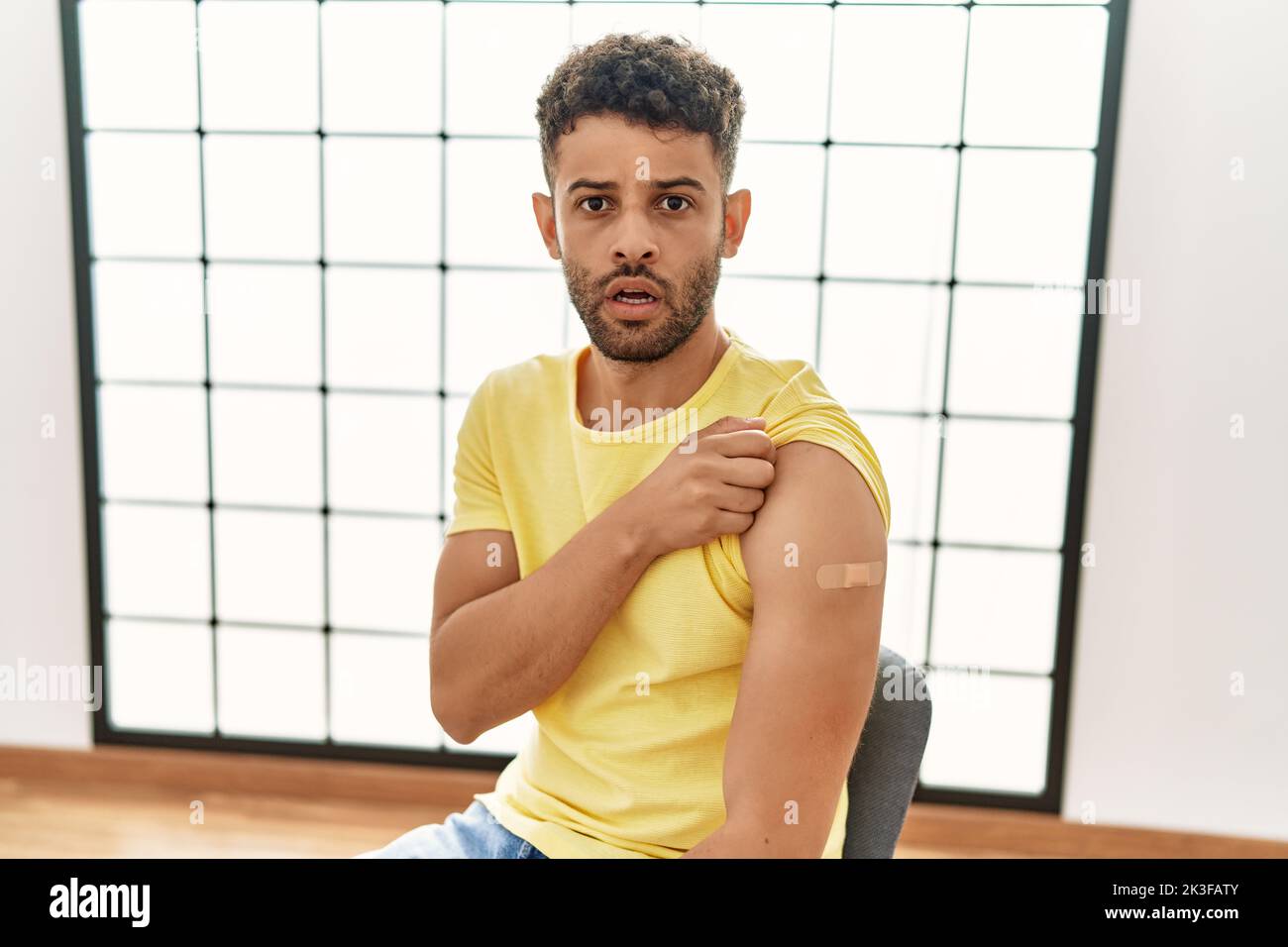 Arab young man getting vaccine showing arm with band aid scared and ...