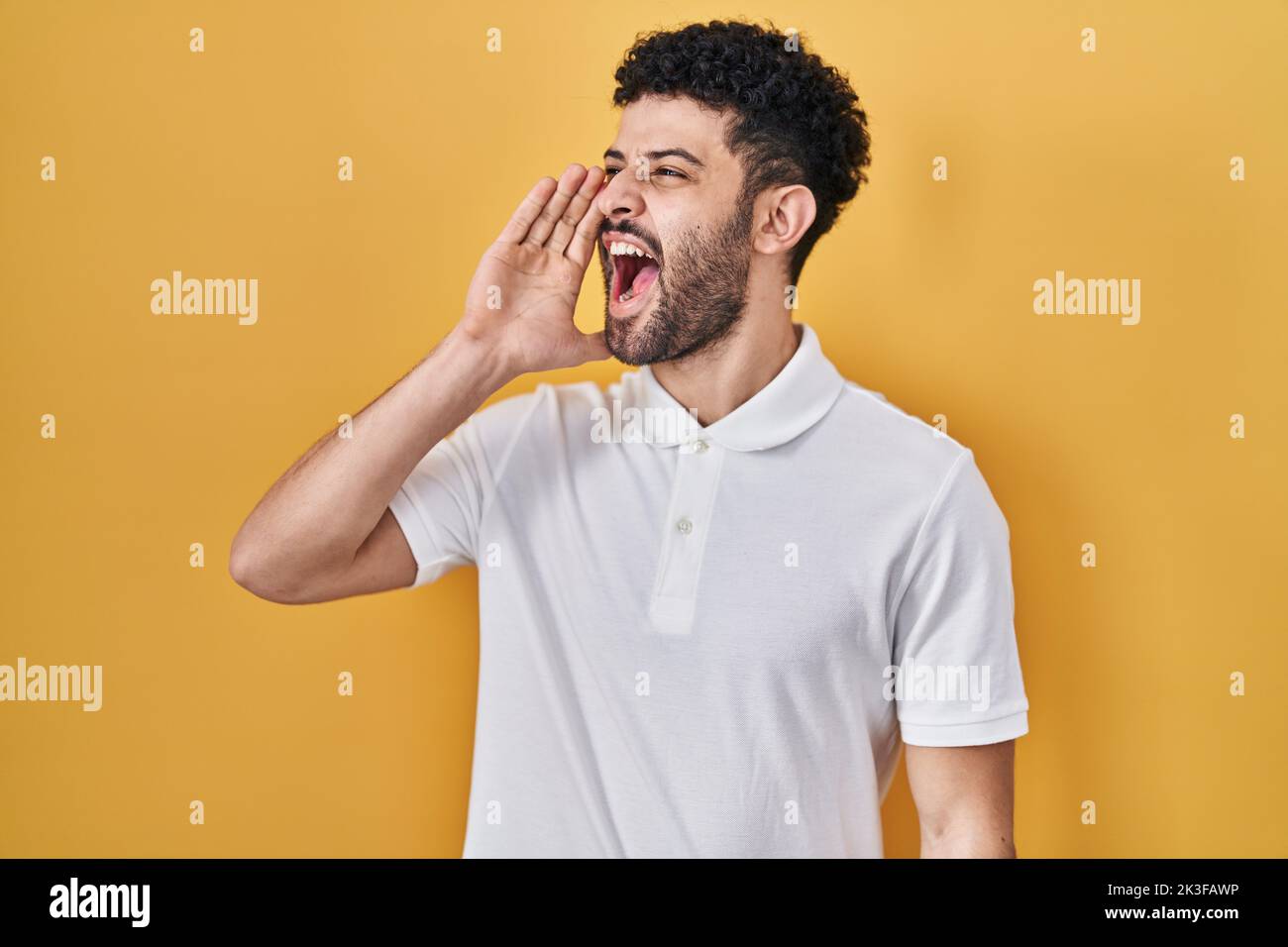 Arab man standing over yellow background shouting and screaming loud to ...