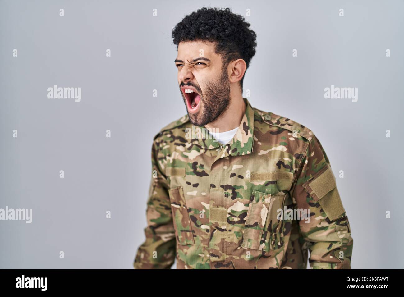 Arab man wearing camouflage army uniform angry and mad screaming ...