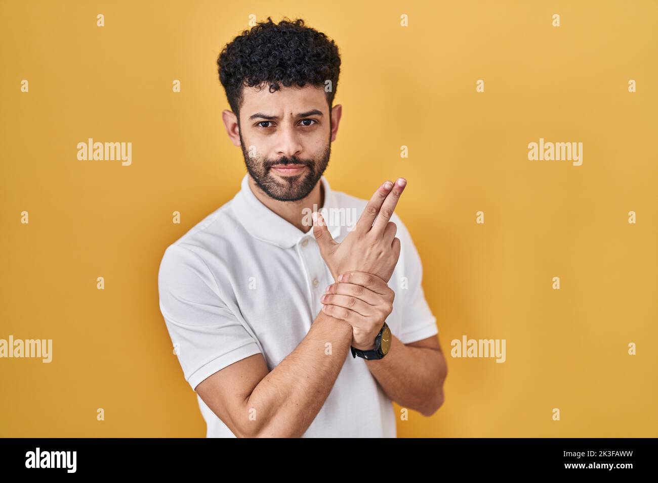 Arab man standing over yellow background holding symbolic gun with hand ...