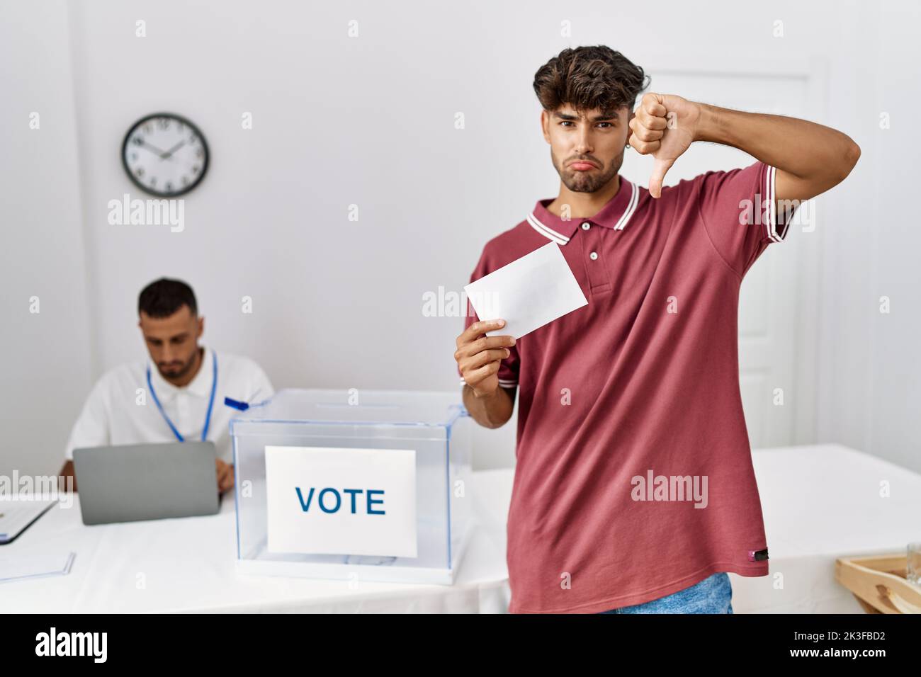 Young hispanic man voting putting envelop in ballot box with angry face ...