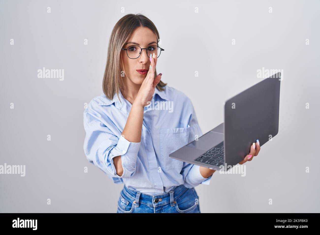Young woman working using computer laptop hand on mouth telling secret ...