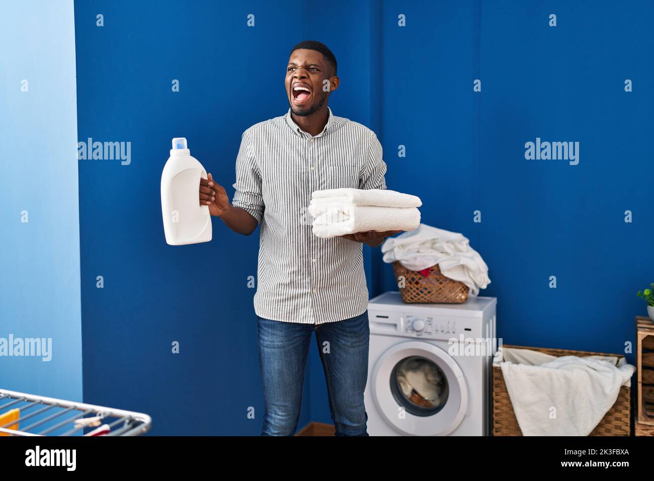 African american man holding clean towels angry and mad screaming ...