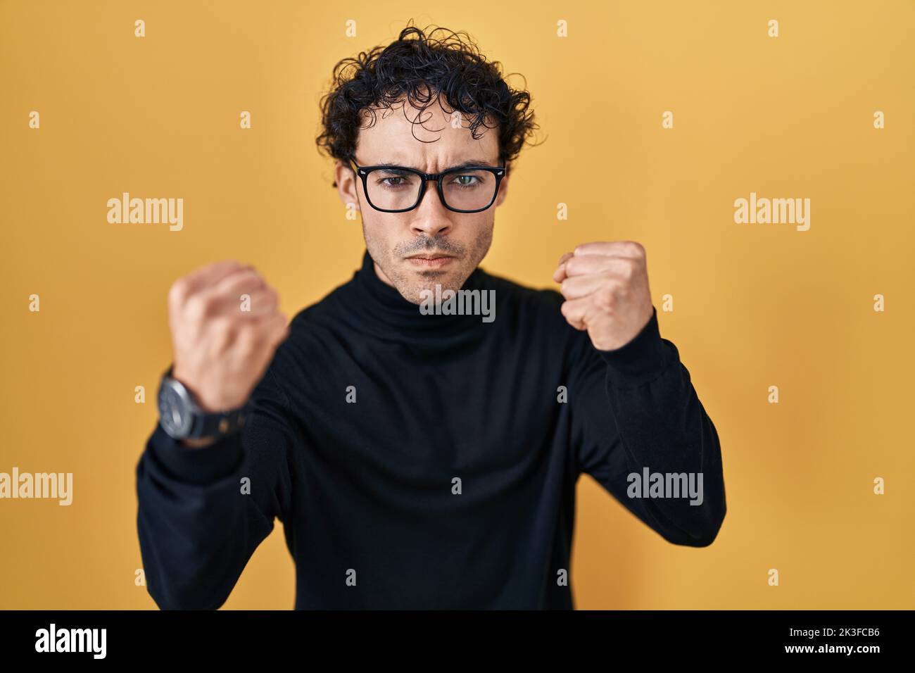 Hispanic man standing over yellow background angry and mad raising ...