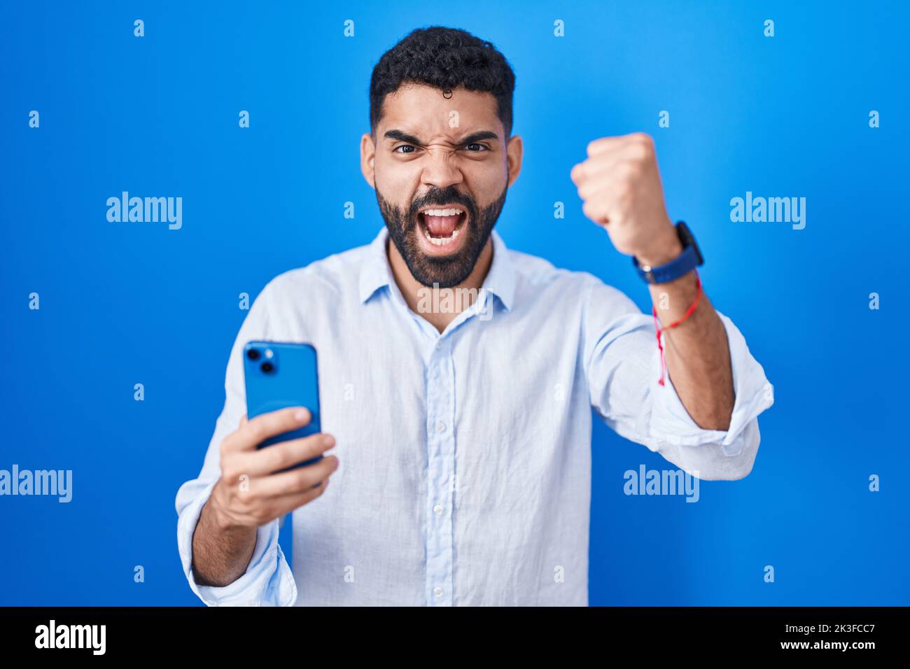Hispanic Man With Beard Using Smartphone Typing Message Angry And Mad
