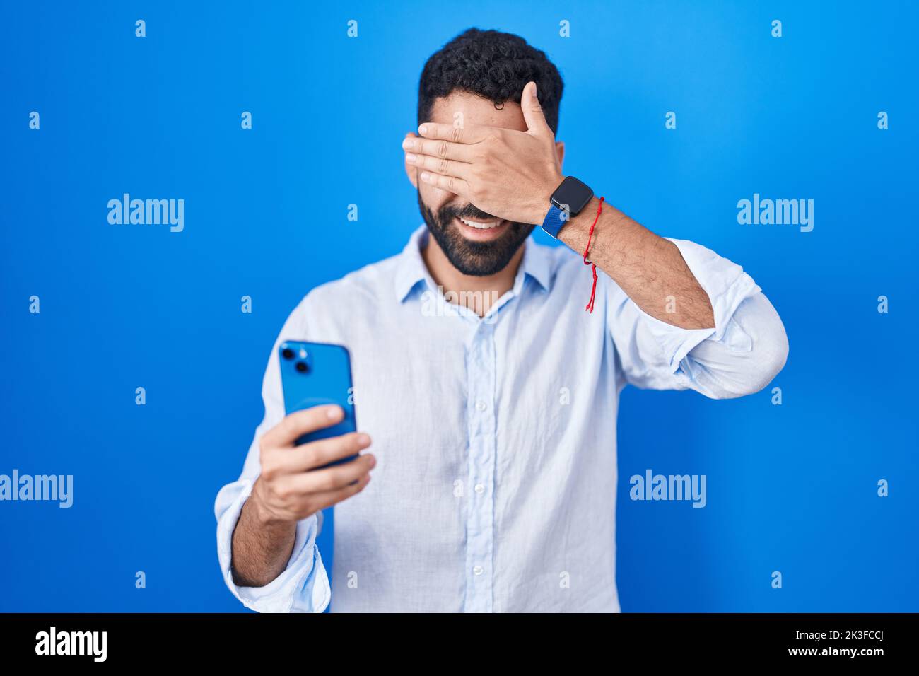 Hispanic man with beard using smartphone typing message smiling and ...