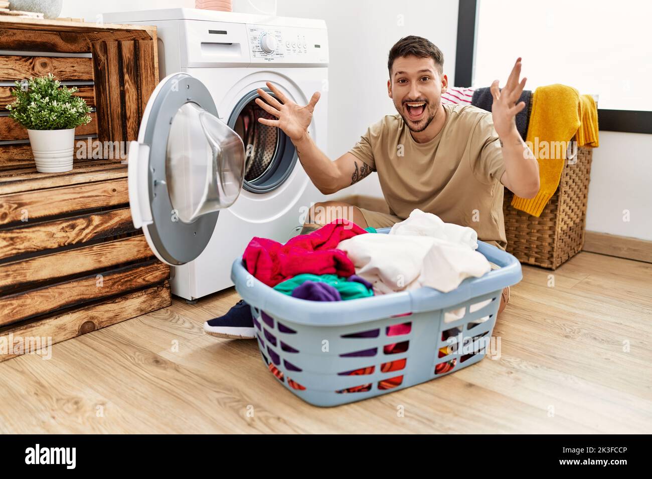 Young handsome man putting dirty laundry into washing machine ...