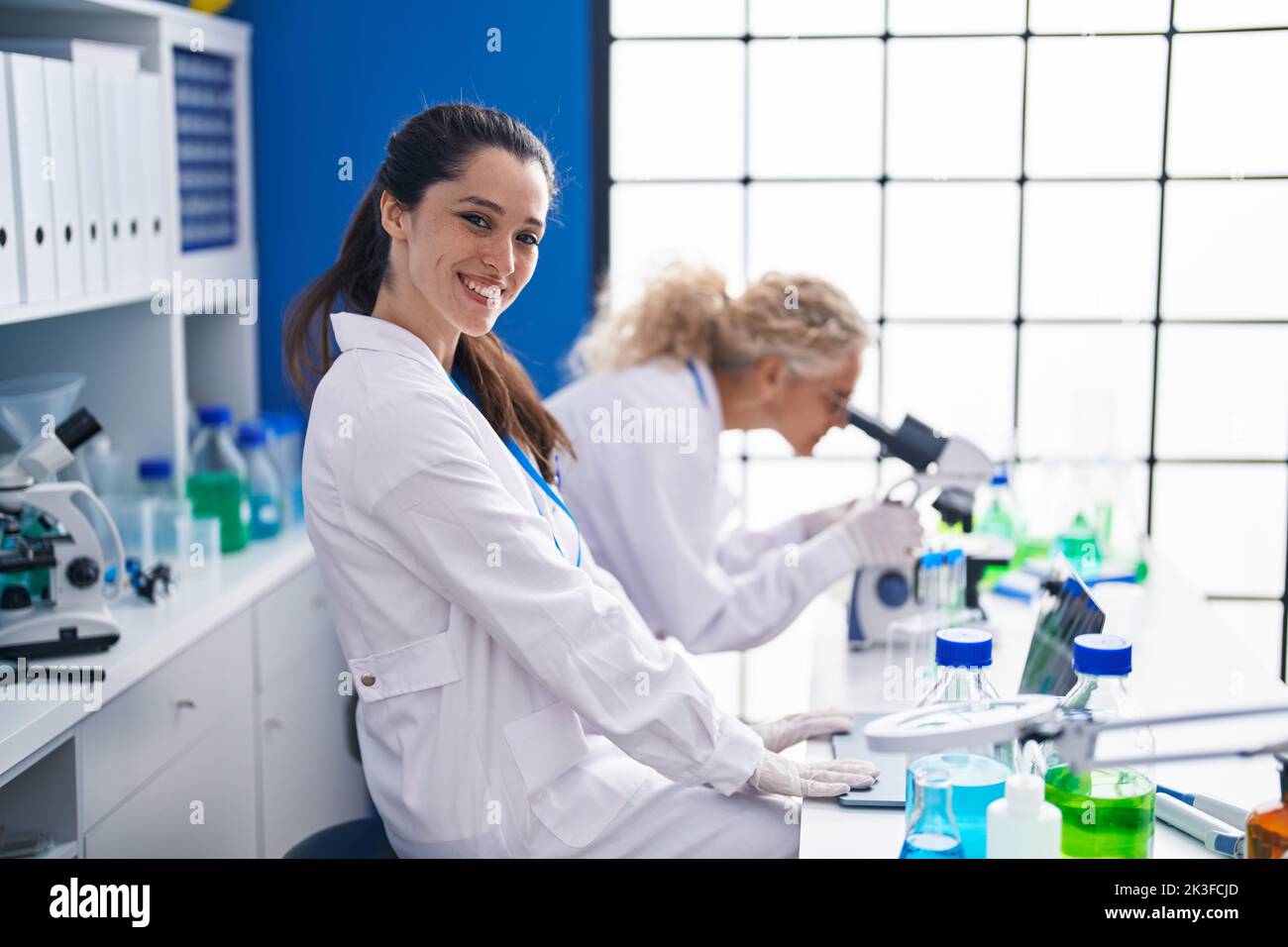 Two women scientists using microscope working at laboratory Stock Photo ...