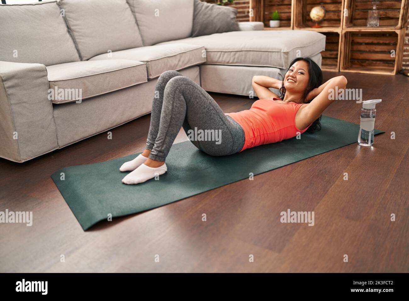 Young chinese woman smiling confident training abs exercise at home ...