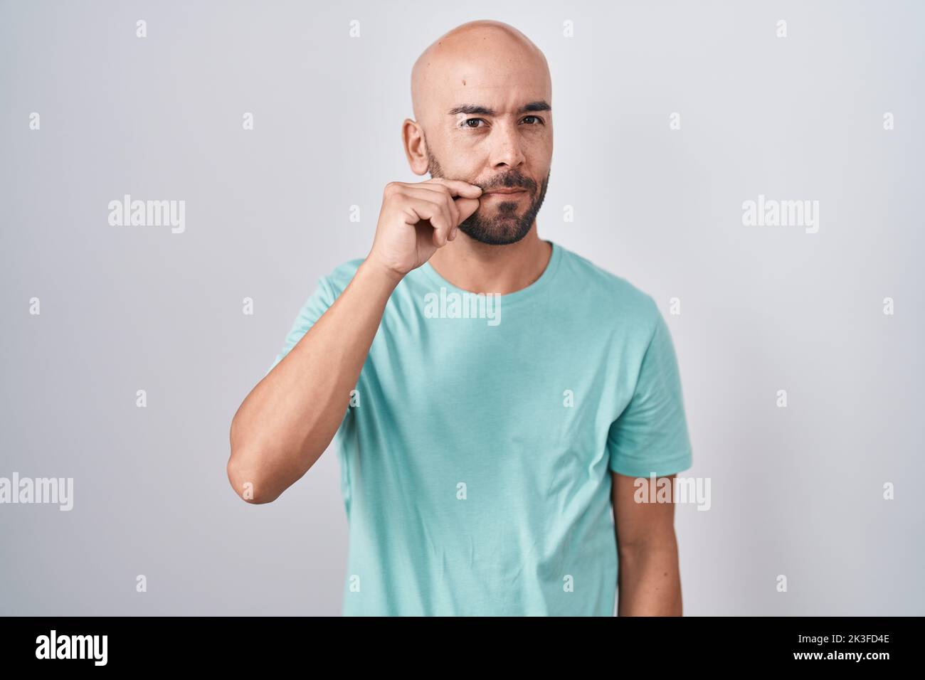 Middle age bald man standing over white background mouth and lips shut ...