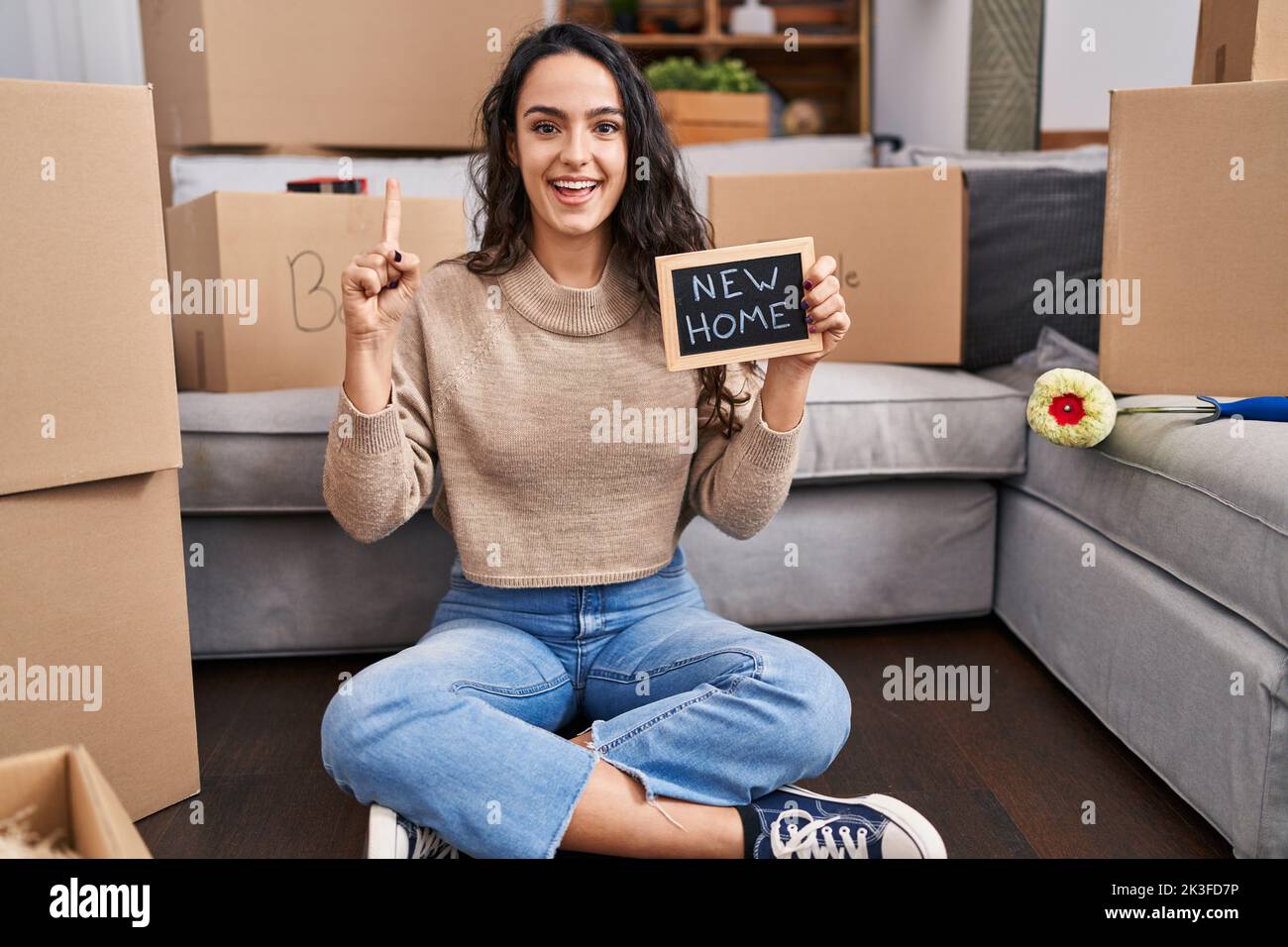 Young brunette woman moving to a new home smiling with an idea or ...
