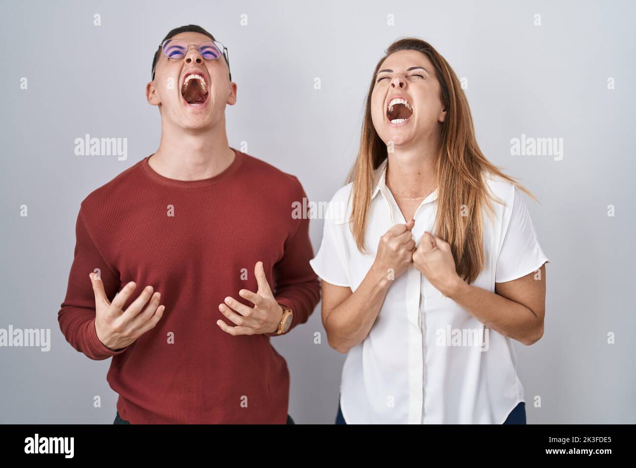 Mother and son standing together over isolated background angry and mad ...