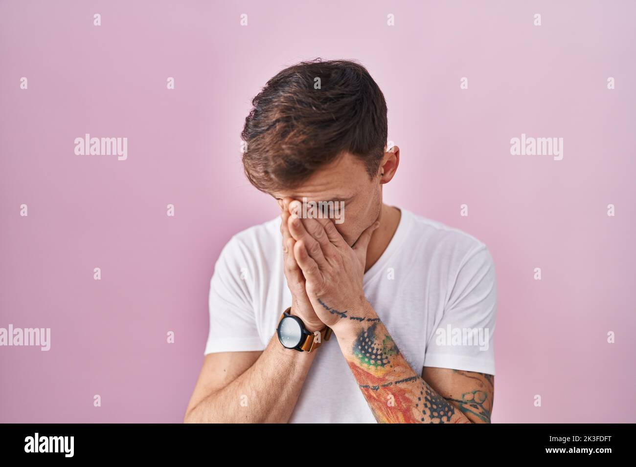 Caucasian man standing over pink background with sad expression ...