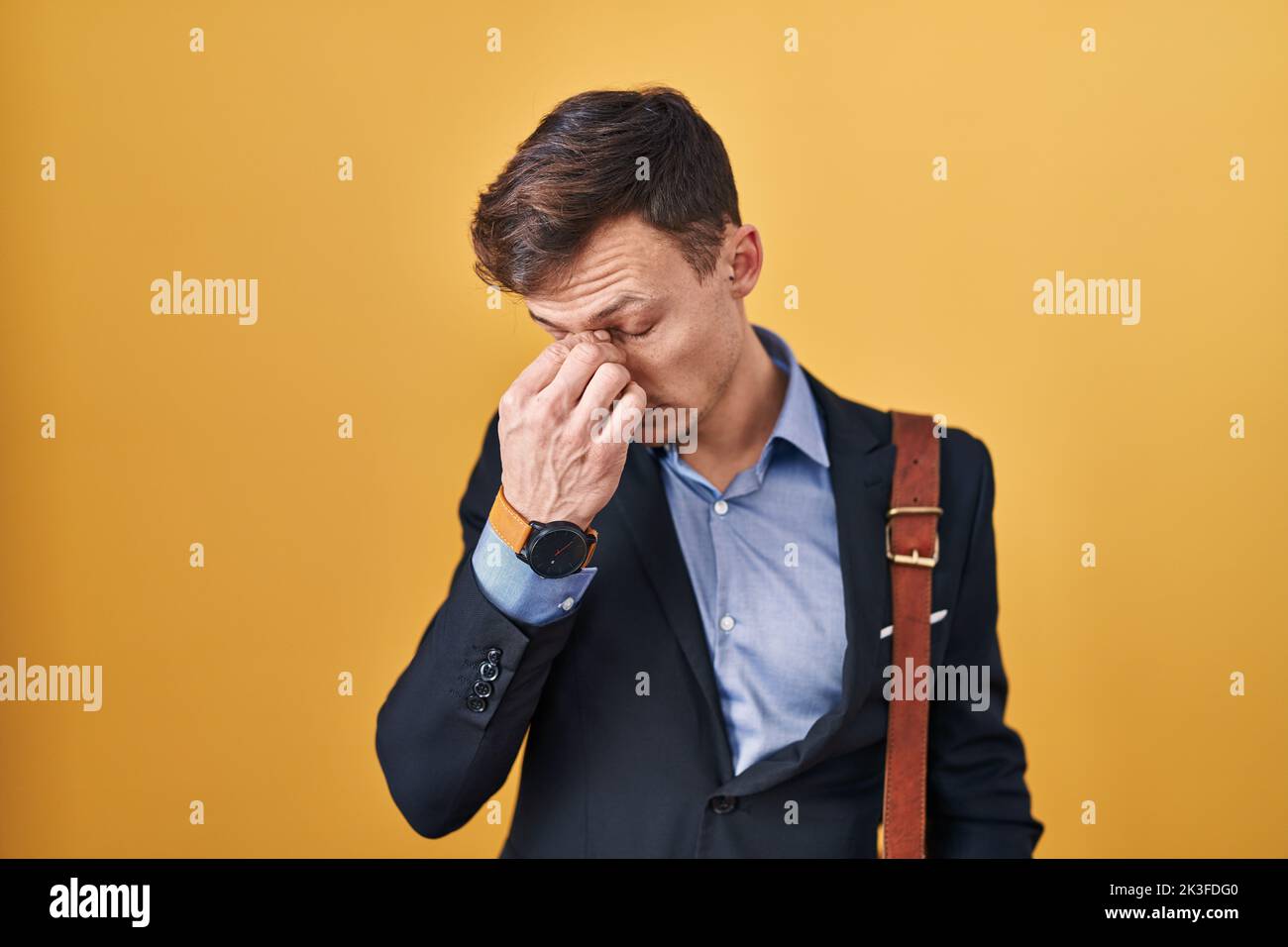 Caucasian business man over yellow background tired rubbing nose and ...