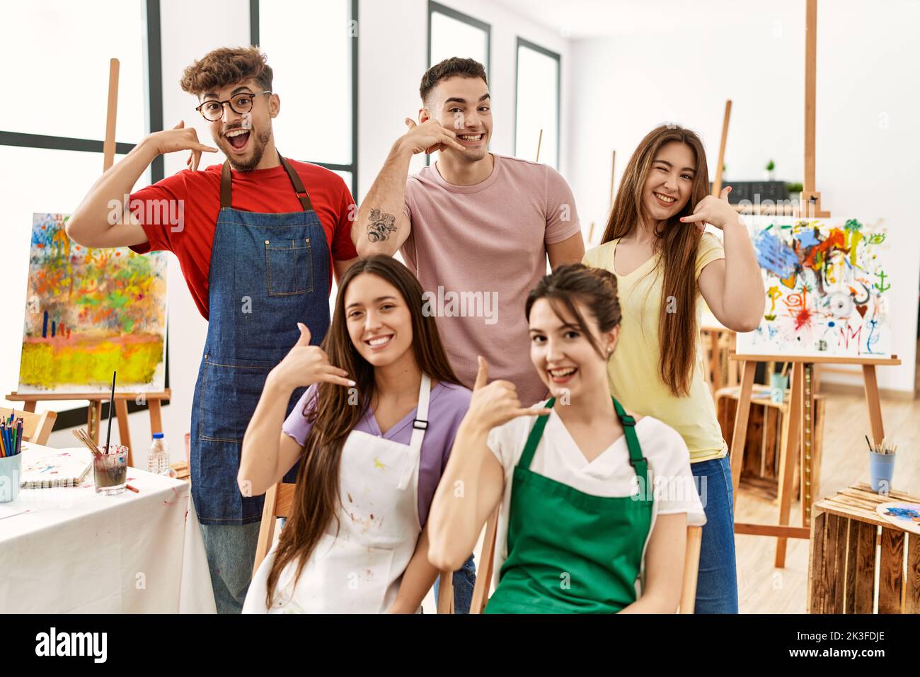 Group of five hispanic artists at art studio smiling doing phone ...