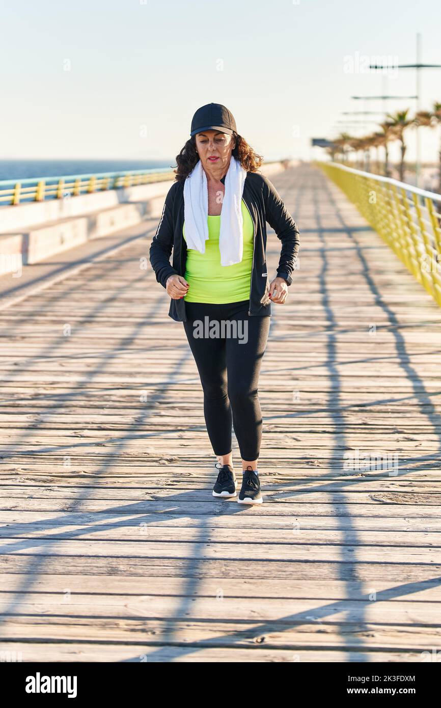 Middle age hispanic woman running at promenade Stock Photo - Alamy