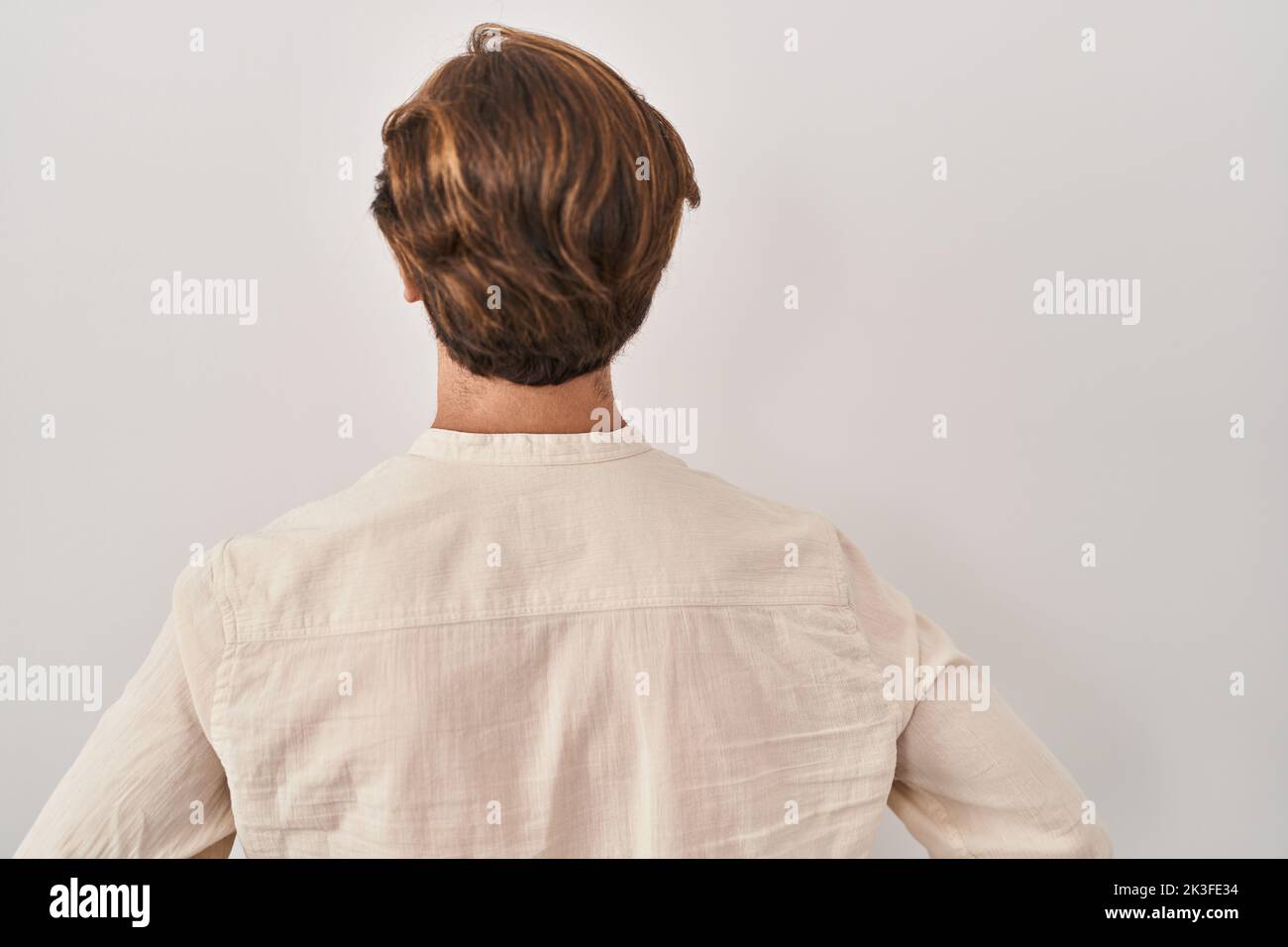 Young man standing over isolated background standing backwards looking ...