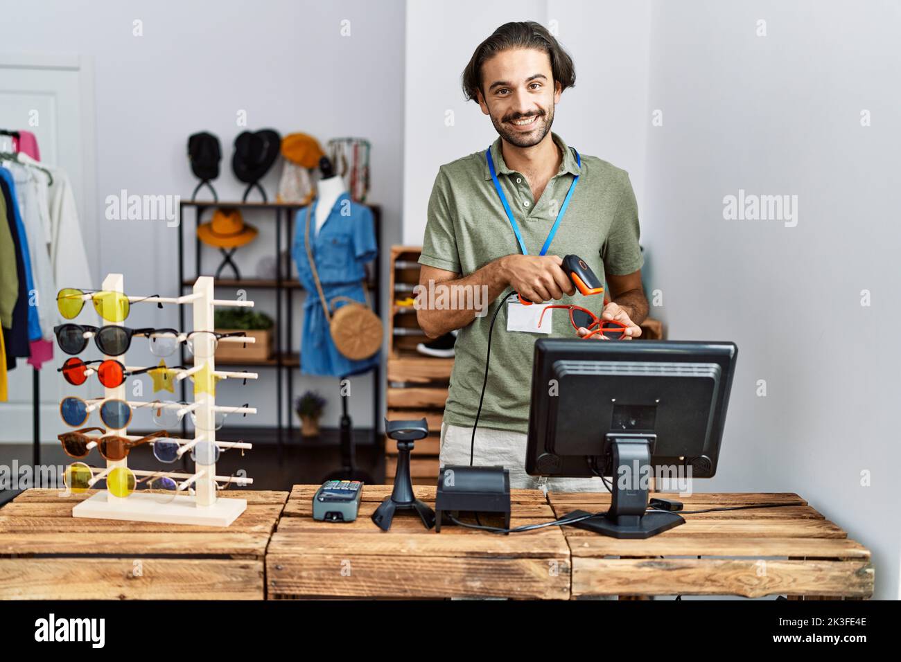 Handsome hispanic man working at shop using barcode scanner at retail ...