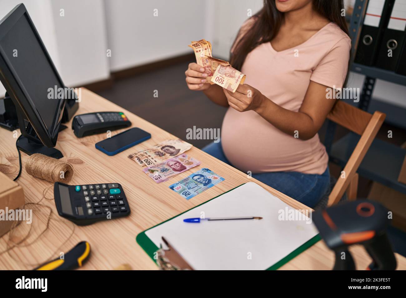 Young latin woman pregnant business worker counting pesos banknotes at ...