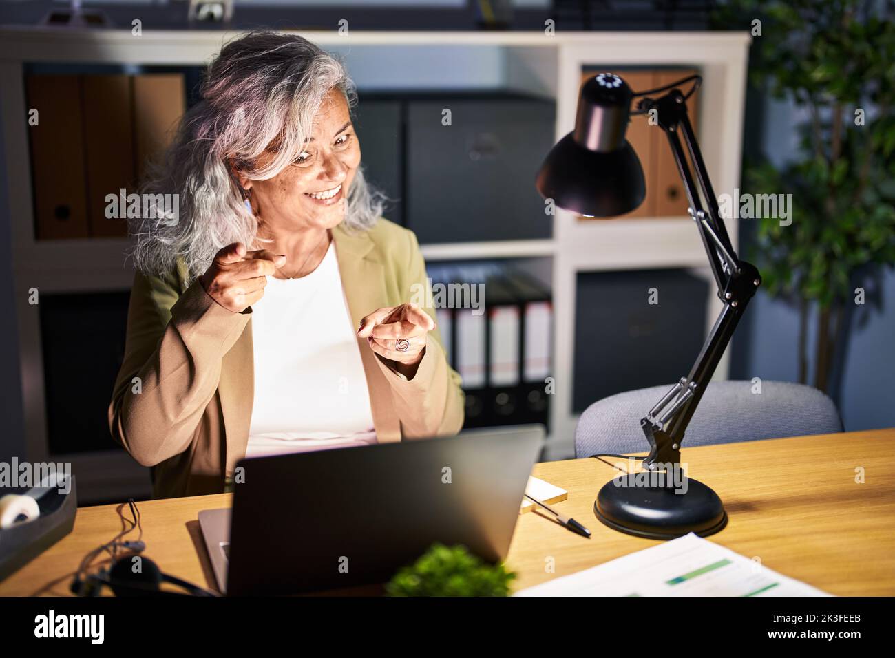 Middle age woman with grey hair working using computer laptop late at ...